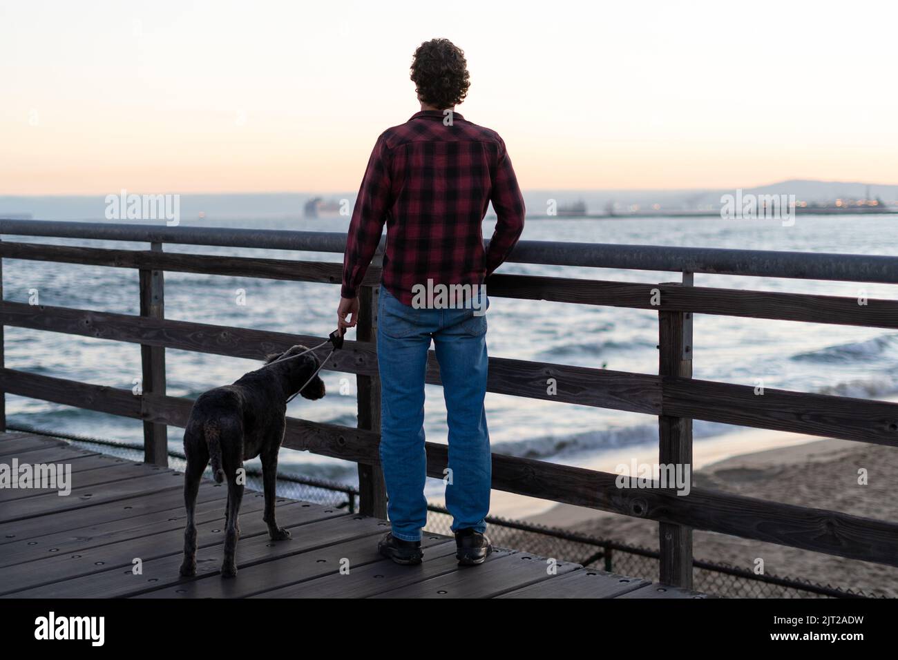 A male walking with his dog on the pier during the sunset Stock Photo ...