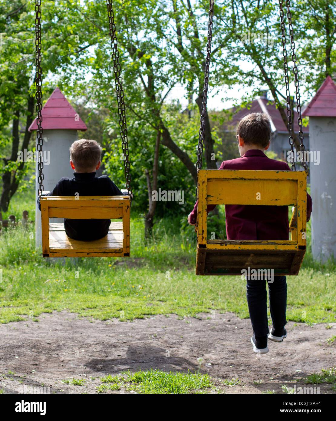 Two cheerful boys ride on swing Stock Photo - Alamy