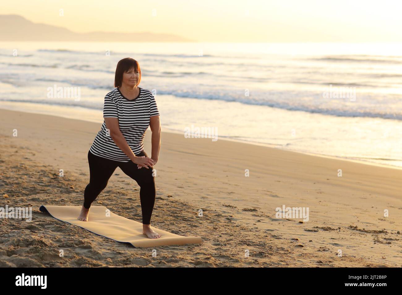 healthy yoga middle ages woman workout yoga pose on mat on the sandy ...