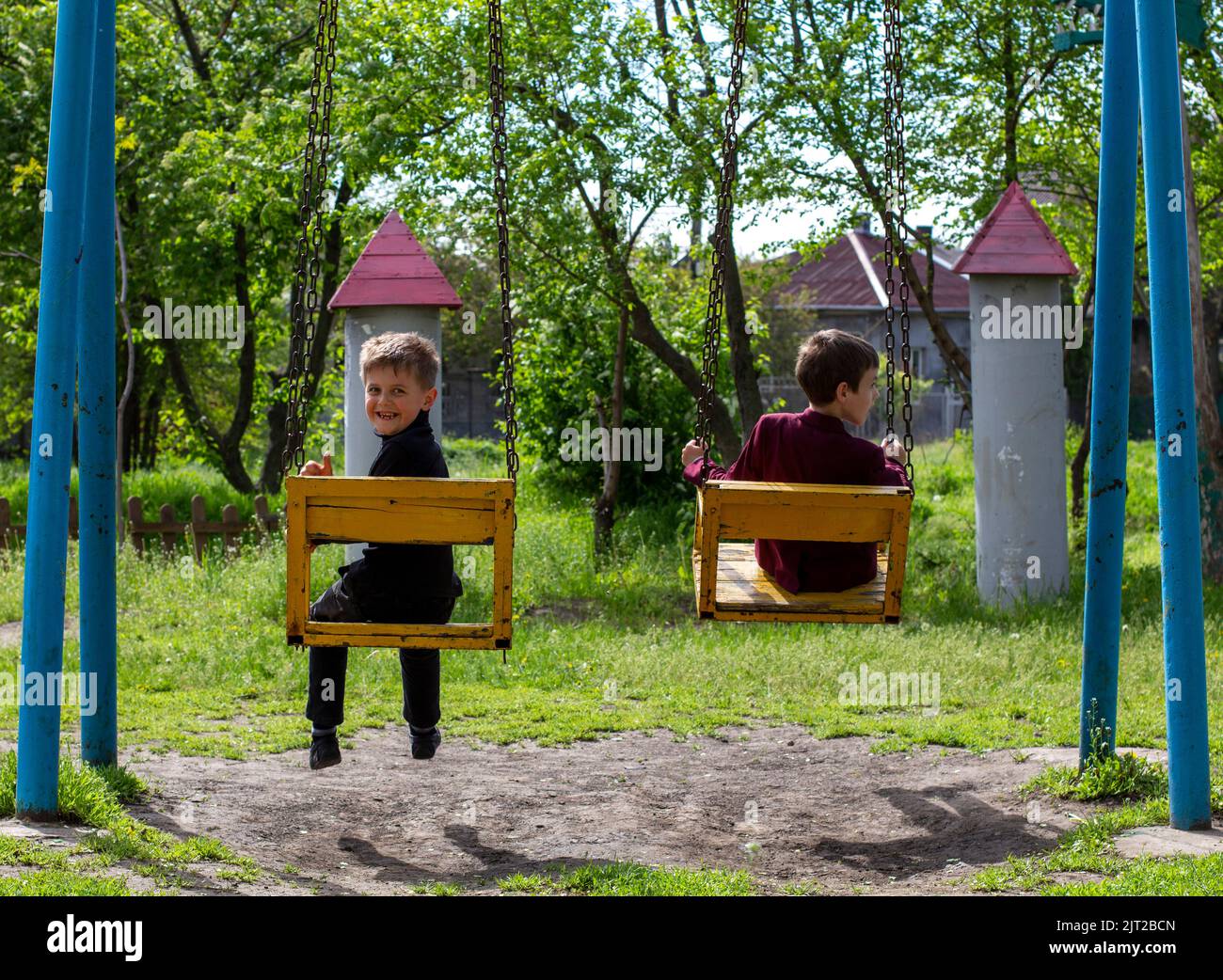 Two cheerful boys ride on swing Stock Photo - Alamy