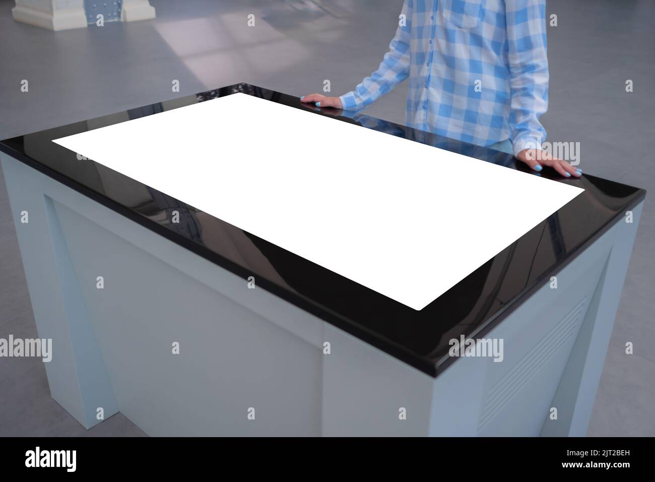 Woman looking at interactive white touchscreen display table kiosk at ...