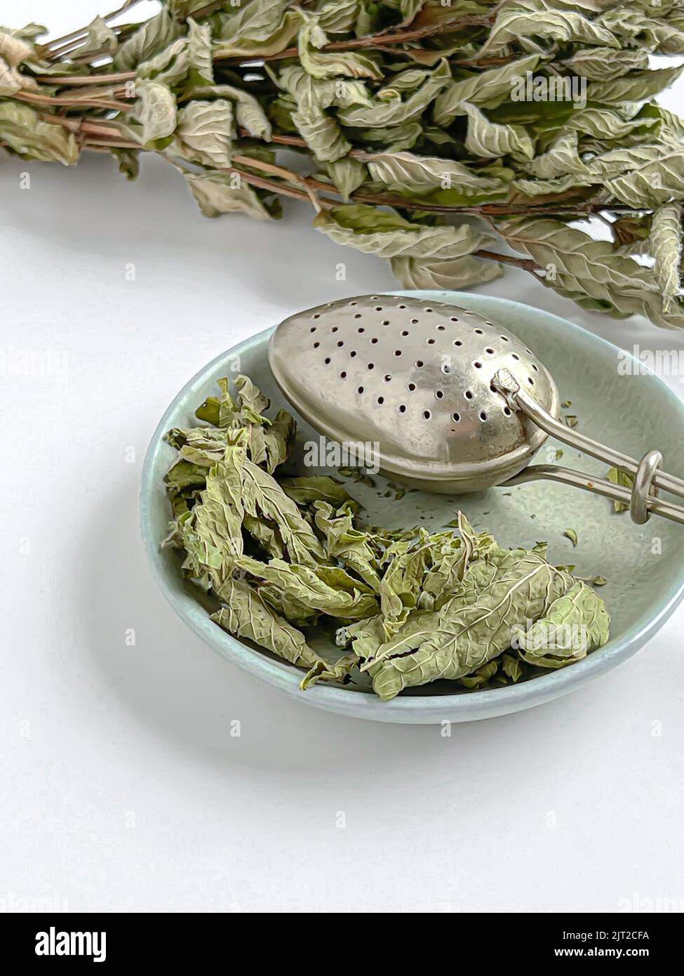 Dried mint leaves in green ceramic bowl on white background. Herbs for ...