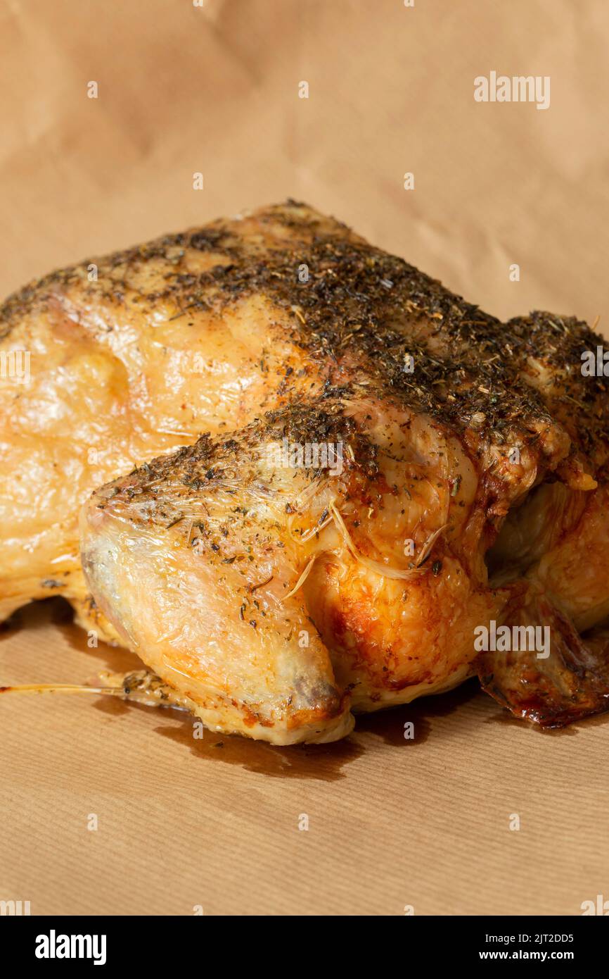 Whole chicken coated in mixed herbs roasted in an oven. On a brown ...