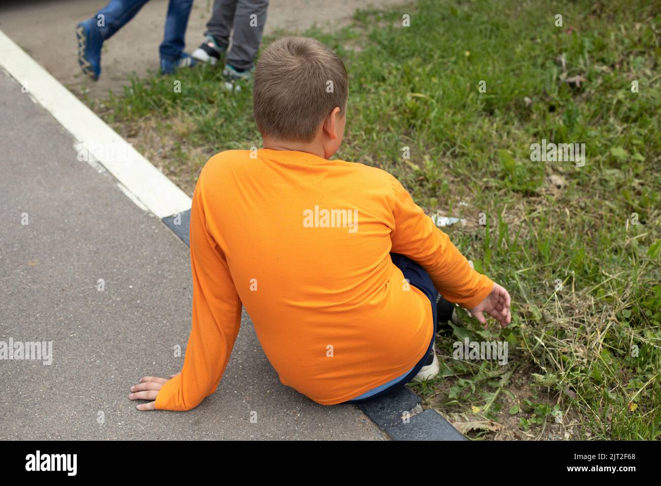Child is sitting on asphalt. Boy on road. Schoolboy is tired. Rest in ...
