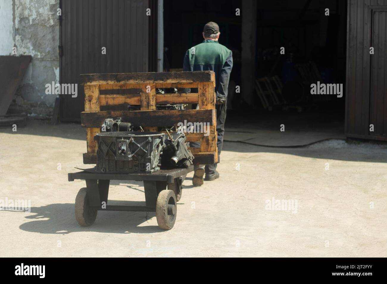 Man carries cart. Worker pulls load. Forklift on street. Man drags ...