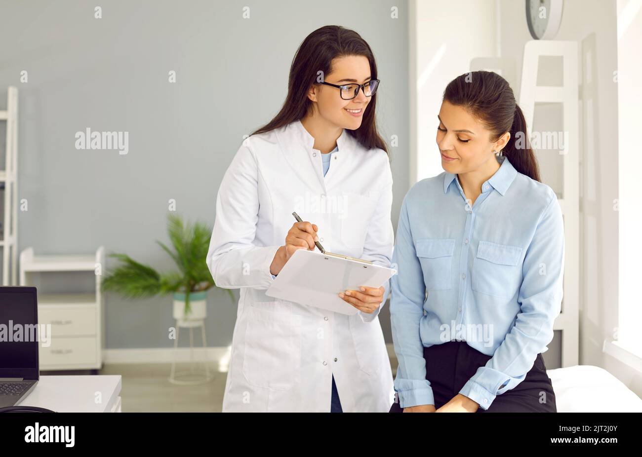 Female doctor writes prescription or makes notes in female patient's ...