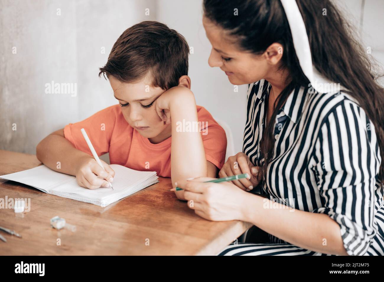 Little school boy doing homework with his mom helping him with ...