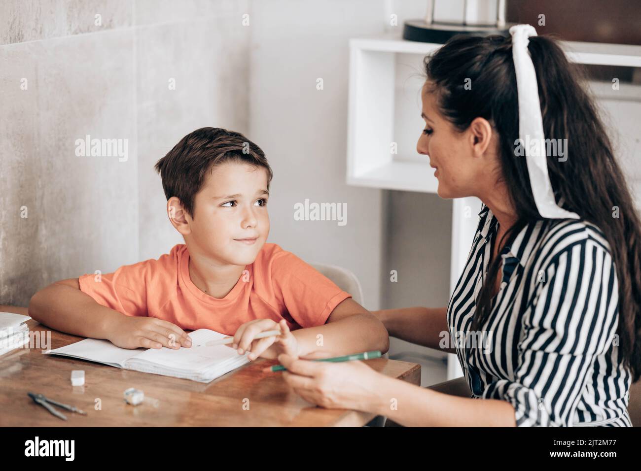 Little school boy doing homework with his mom helping him with ...