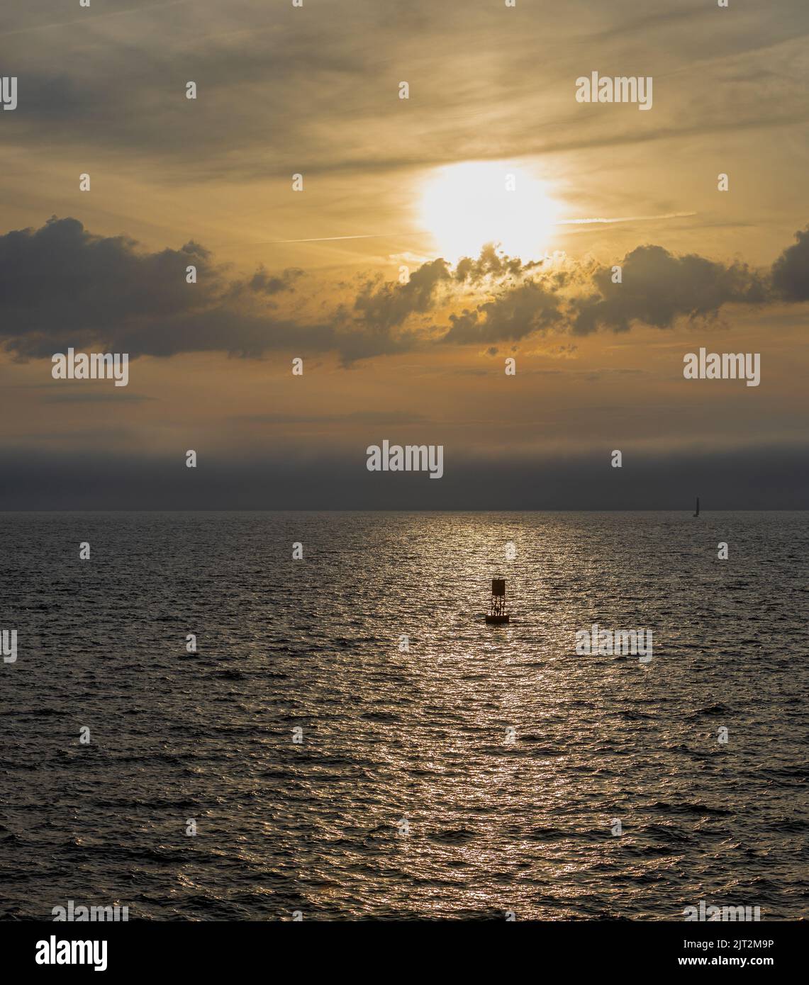 A distant buoy floating on soft Atlantic Ocean waves captured at sunset ...