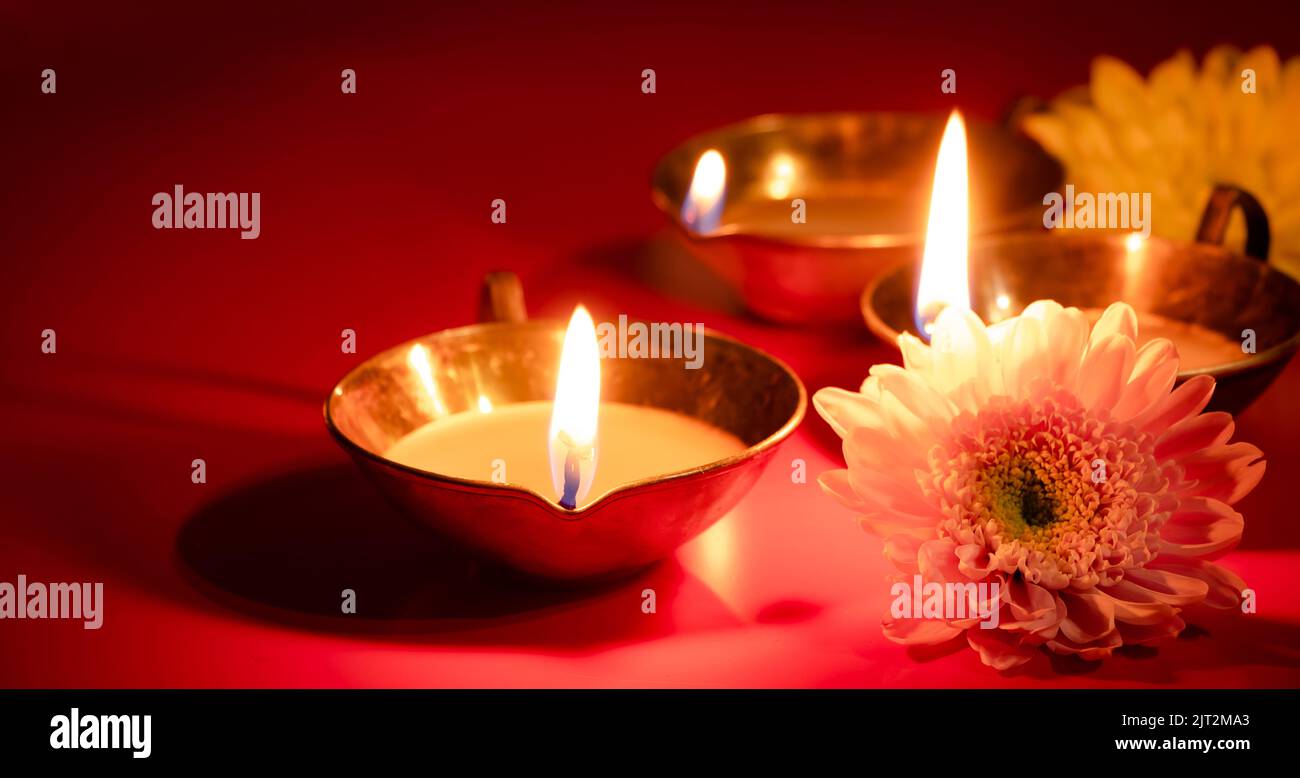 Happy Diwali. Diya oil lamp and flowers on red background. Traditional ...