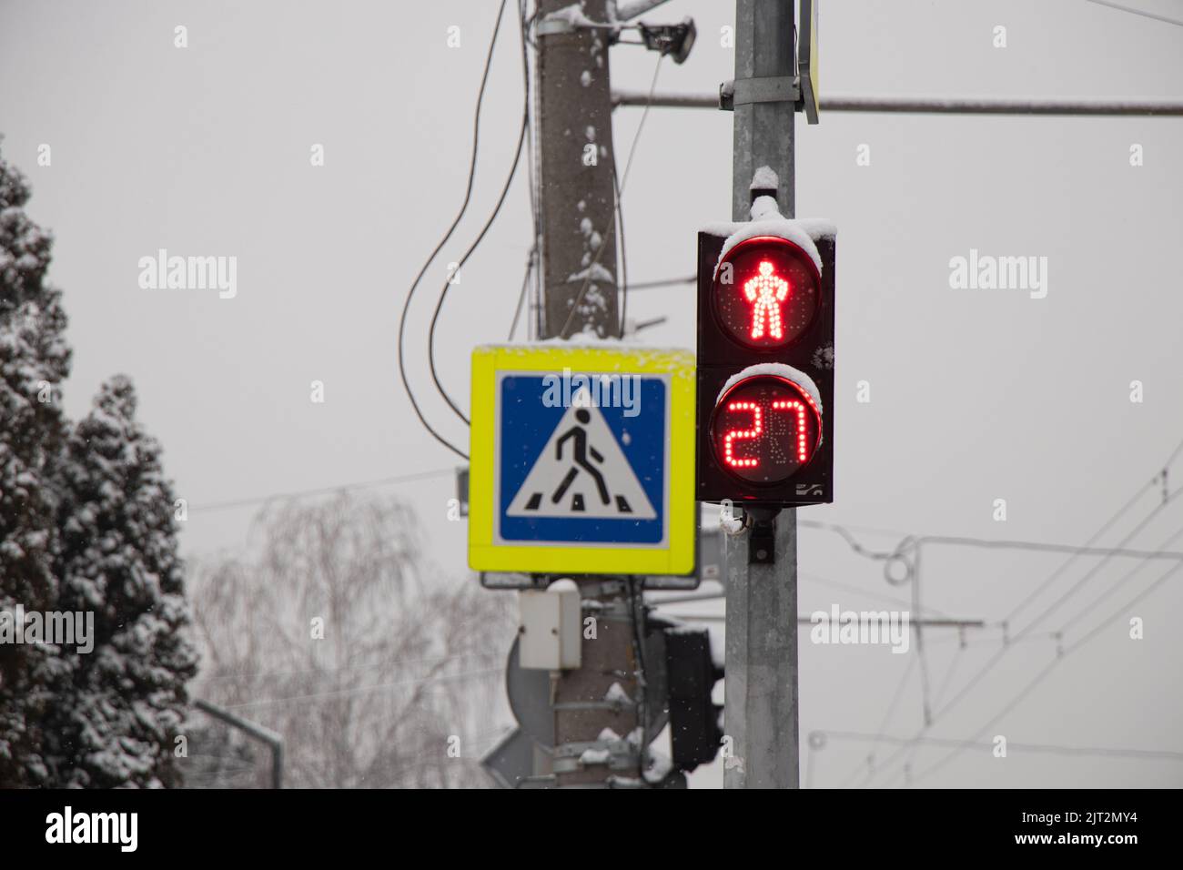 A sign of a pedestrian crossing in winter in the snow in the city drove ...