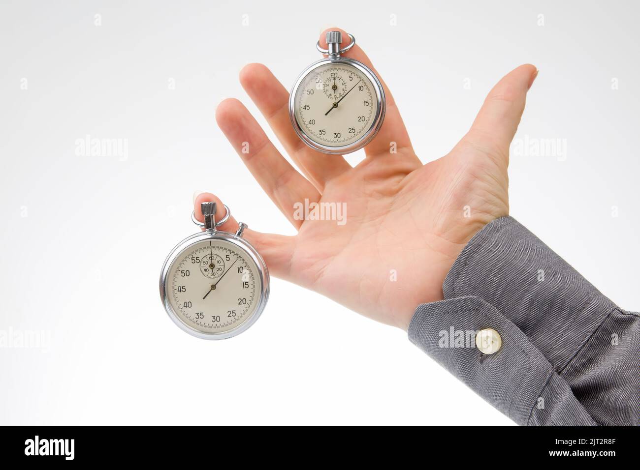 Two mechanical stopwatches hang on the fingers of a male hand. Time ...