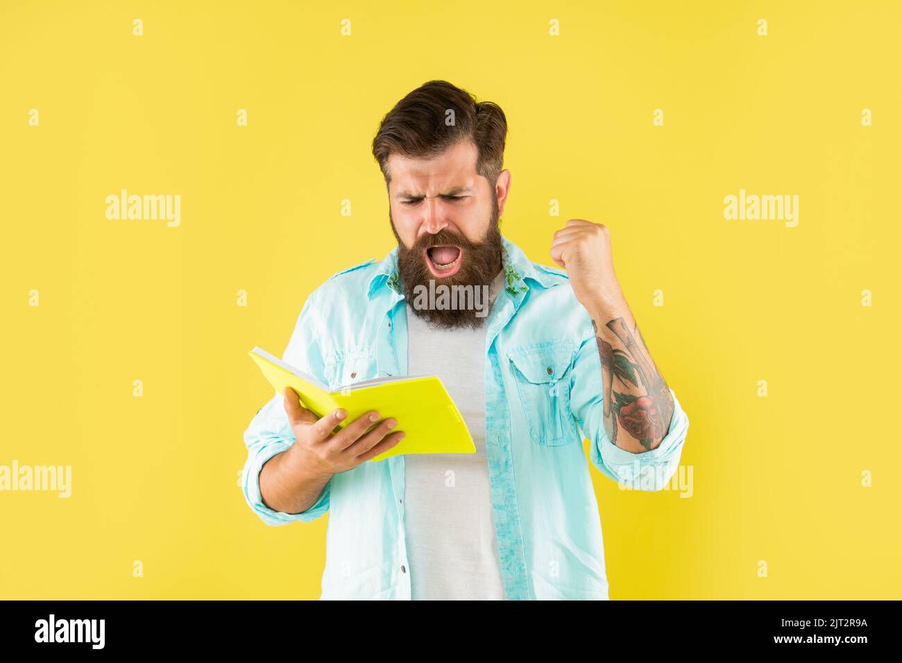 shouting hipster guy reading notebook on yellow background, success ...