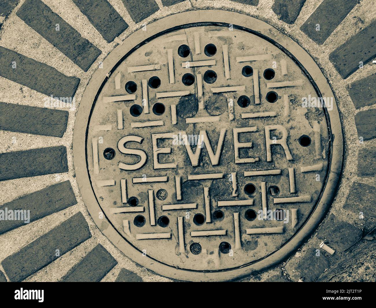 Grimy sewer manhole cover in city street in monochrome Stock Photo - Alamy