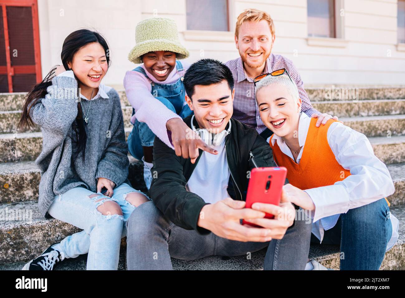Five young friends looking at mobile phone. Group of people sitting ...