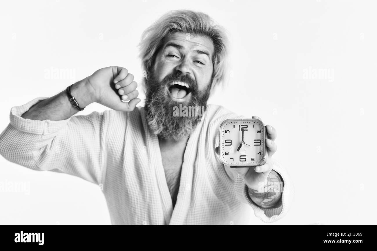 happy handsome angry man lies in bed indoors wake up turn off the alarm ...