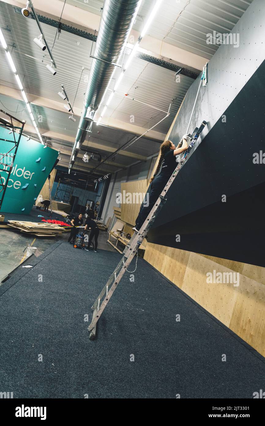 A female worker setting new briar climbing holds at the climbing gym ...