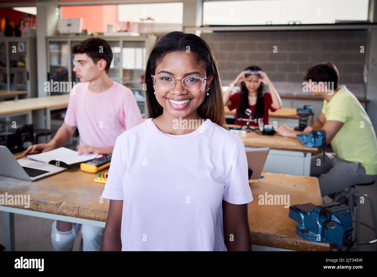 Portrait of a girl standing in a technology class looking at the camera ...