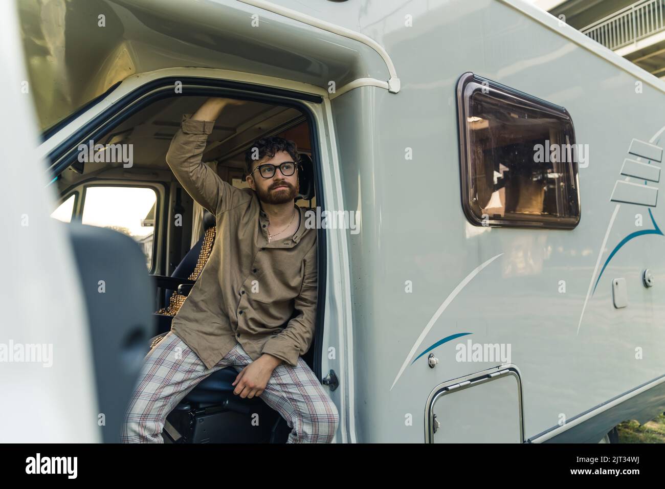 Thoughtful stylish young bearded man sitting on the driver seat of a ...