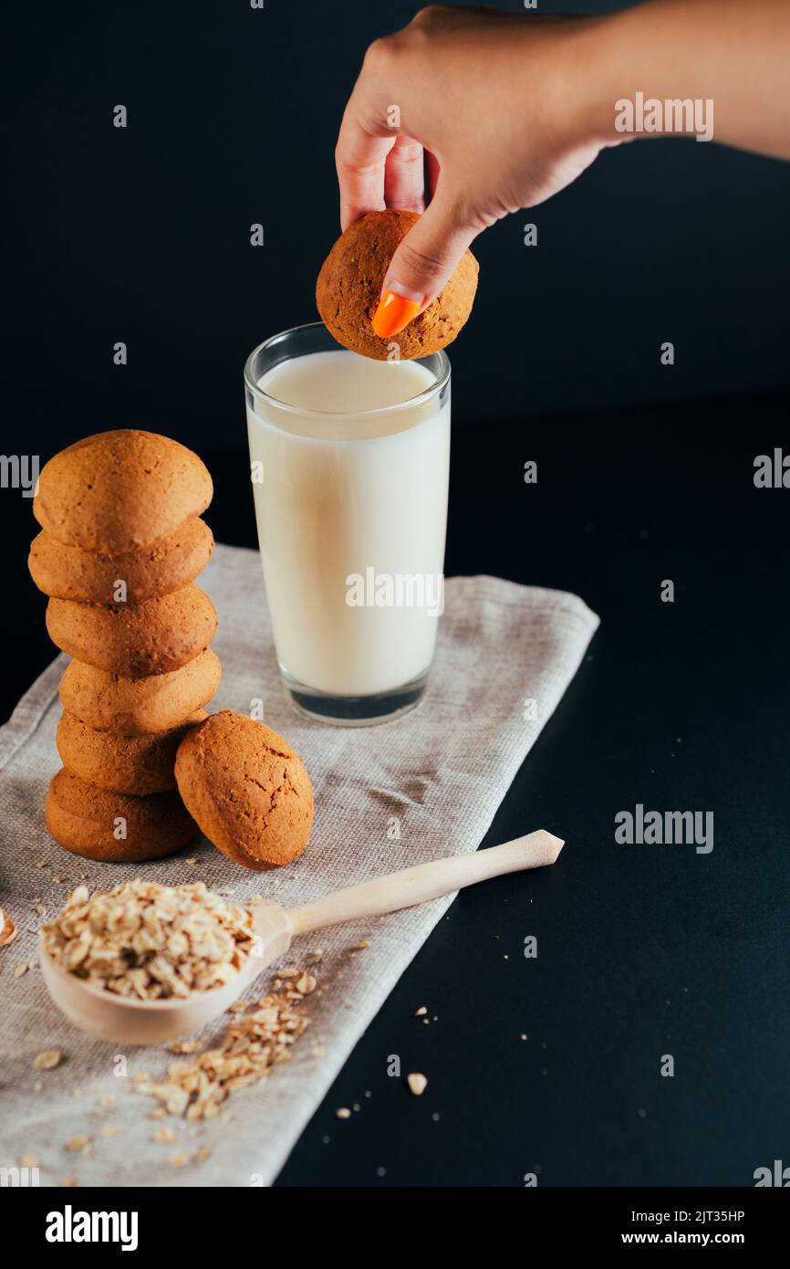 Oatmeal cookies laid out in a stack, a woman's hand soaks cookies in a ...