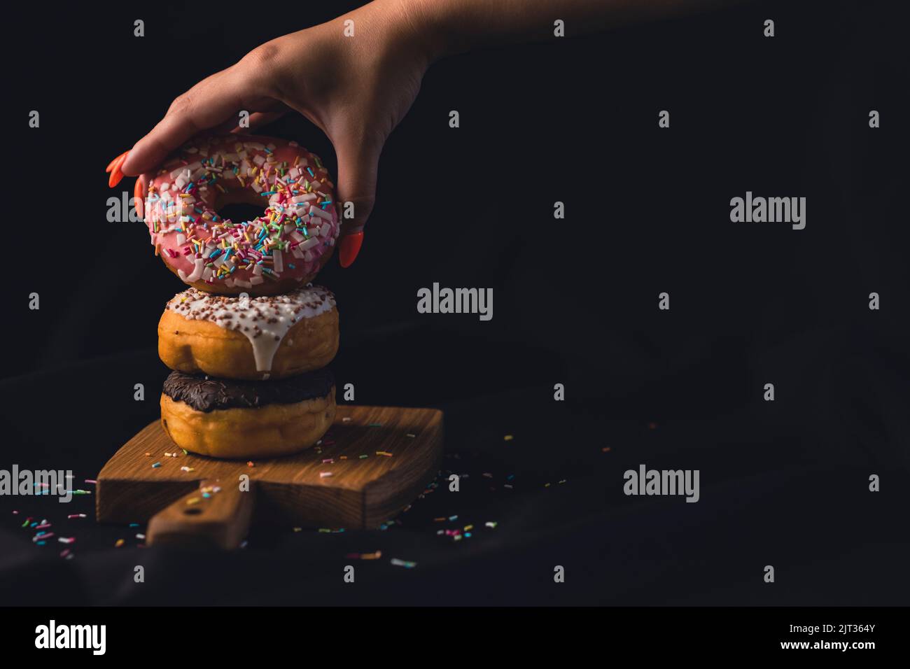 Close-up of a woman's hand taking a delicious donut from a wooden board ...
