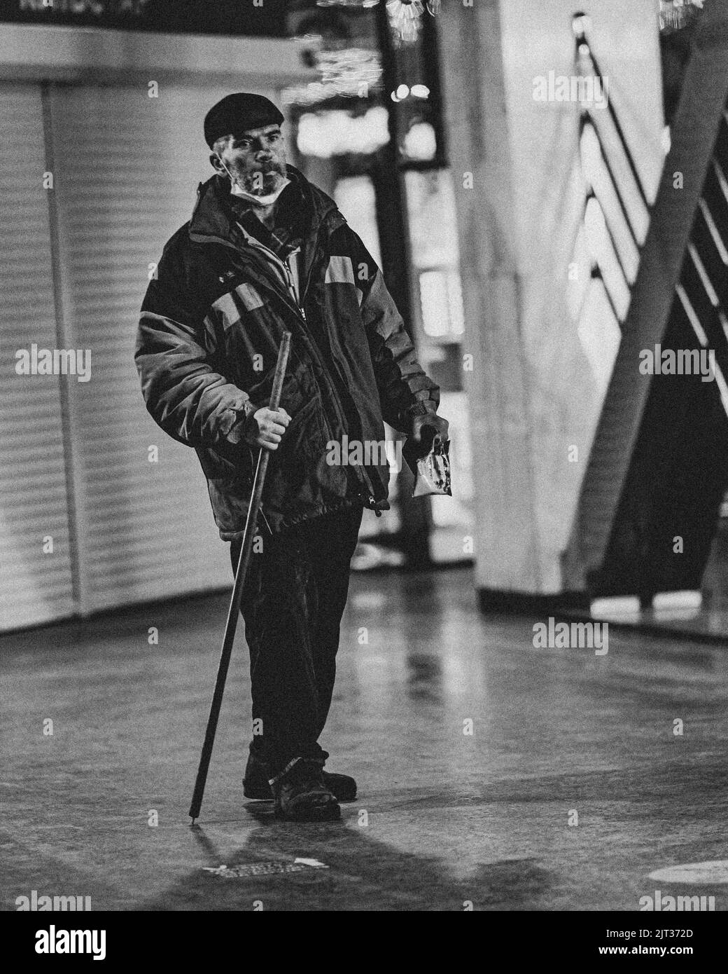 A closeup grayscale shot of a homeless man walking in the street in ...