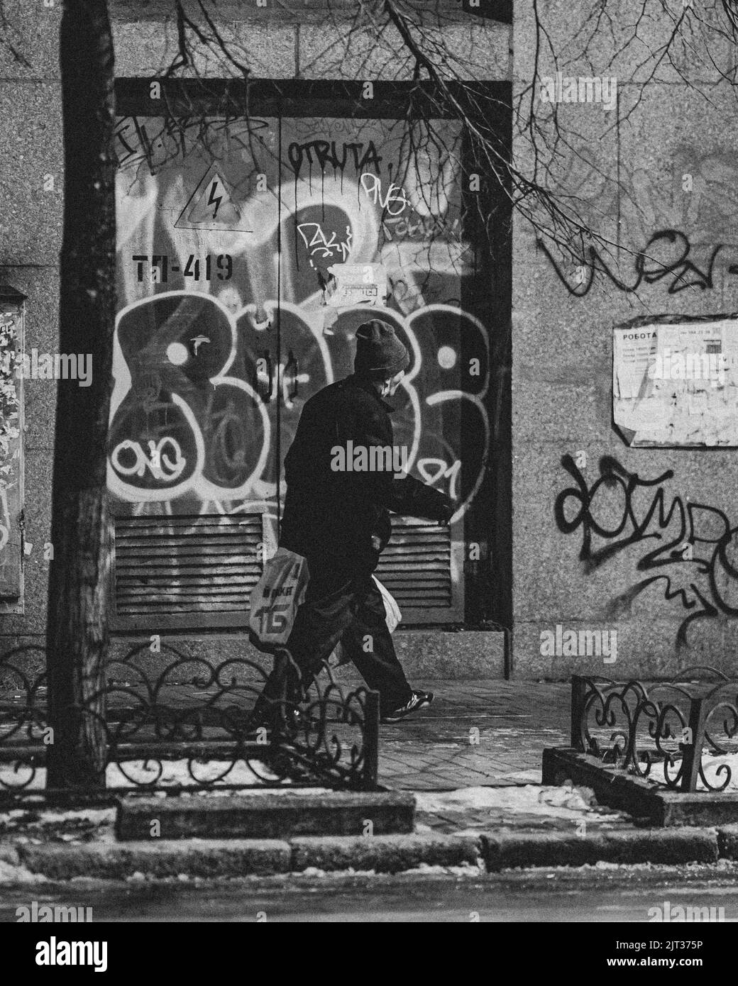 A grayscale of a homeless man walking on a graffiti wall background ...