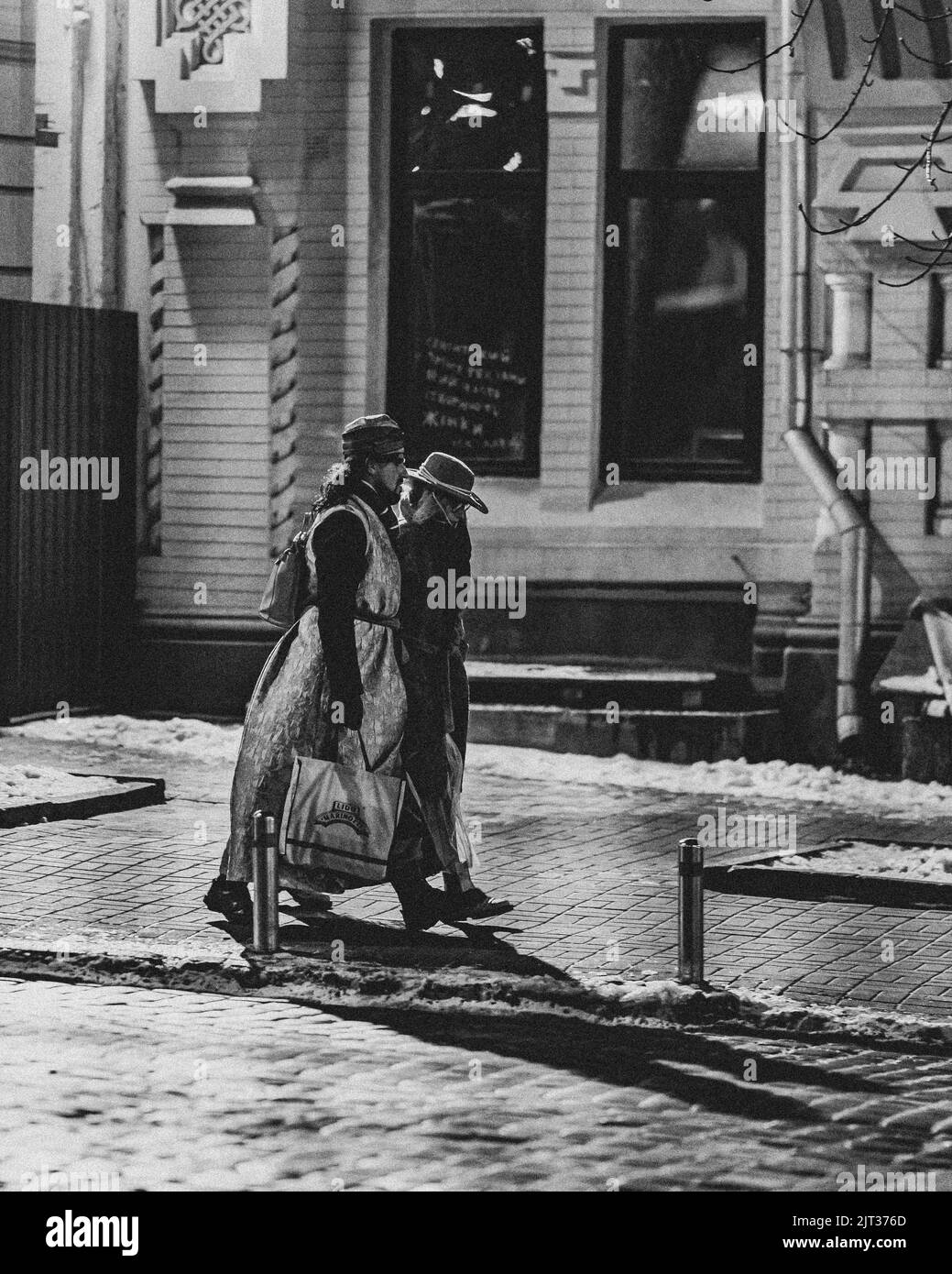 A grayscale shot of homeless men walking on the street at night Stock ...