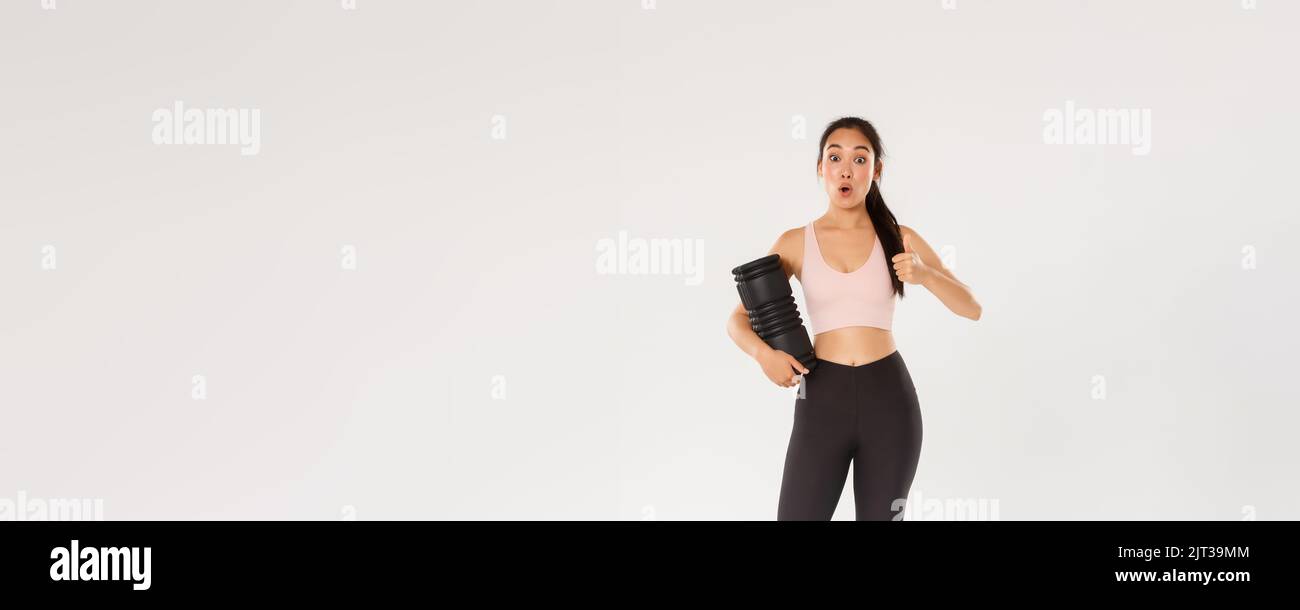Full length of impressed and satisfied asian female athlete, fitness ...