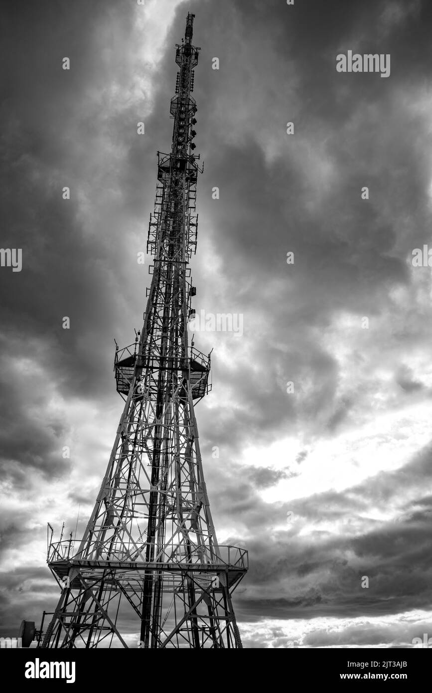 A grayscale of a Telecommunication tower with a cloudy sky background ...