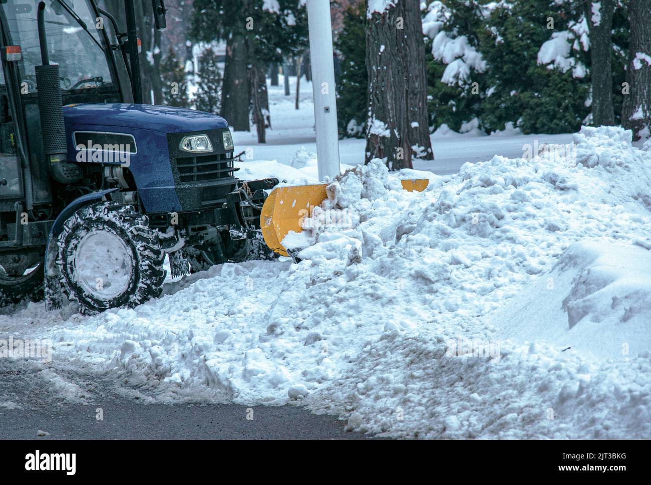 Blue tractor cleans city streets and roads after heavy snowfall ...