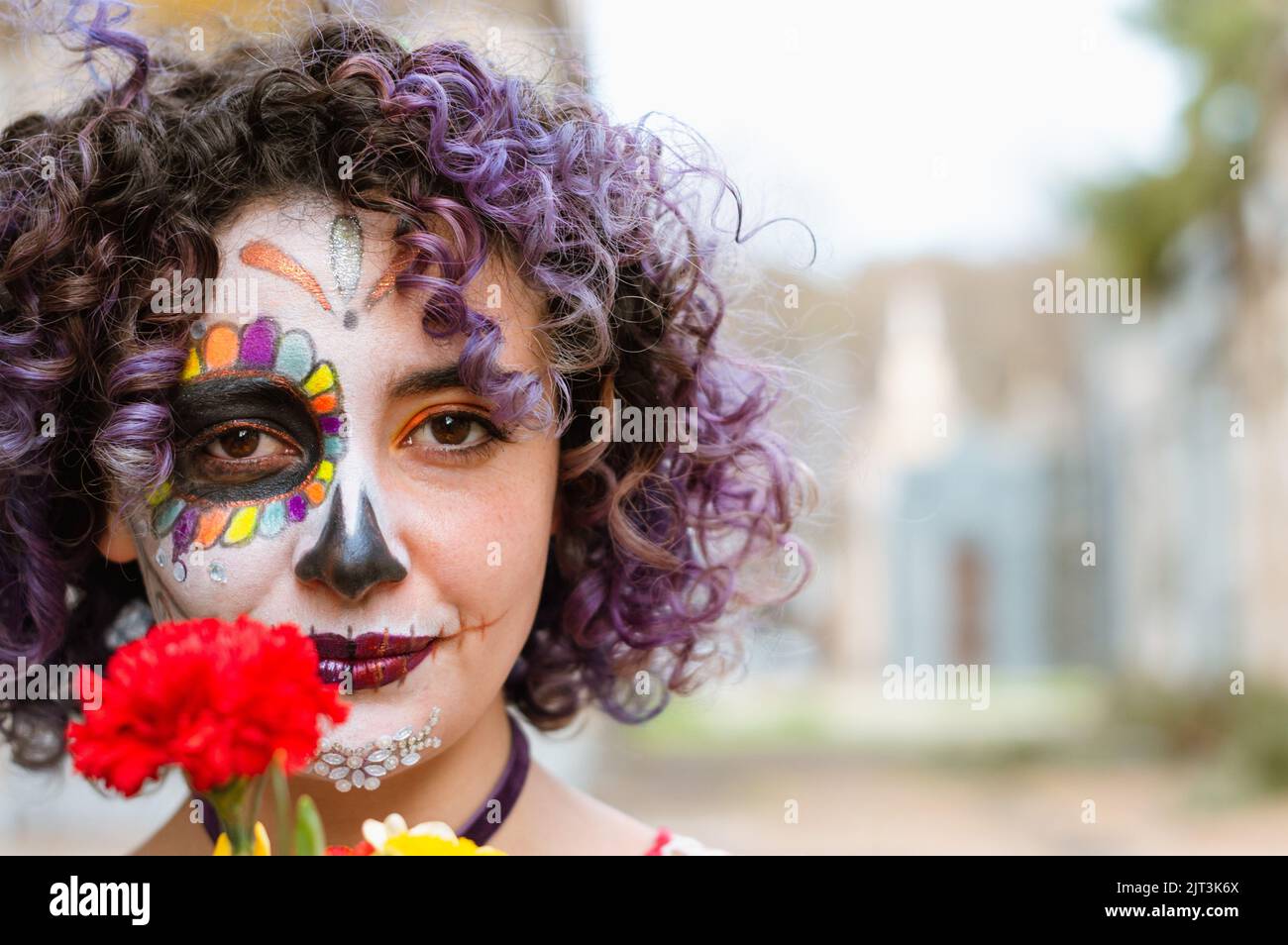 portrait of beautiful young latin woman outdoors looking at camera and smiling, holding a red ...