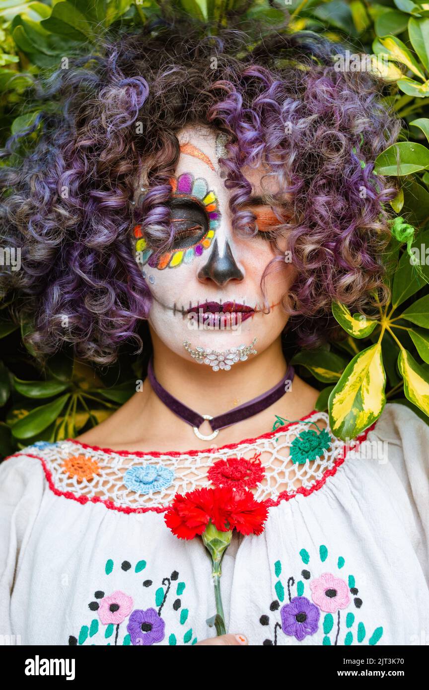 vertical portrait of young latin woman with closed eyes, purple curly ...