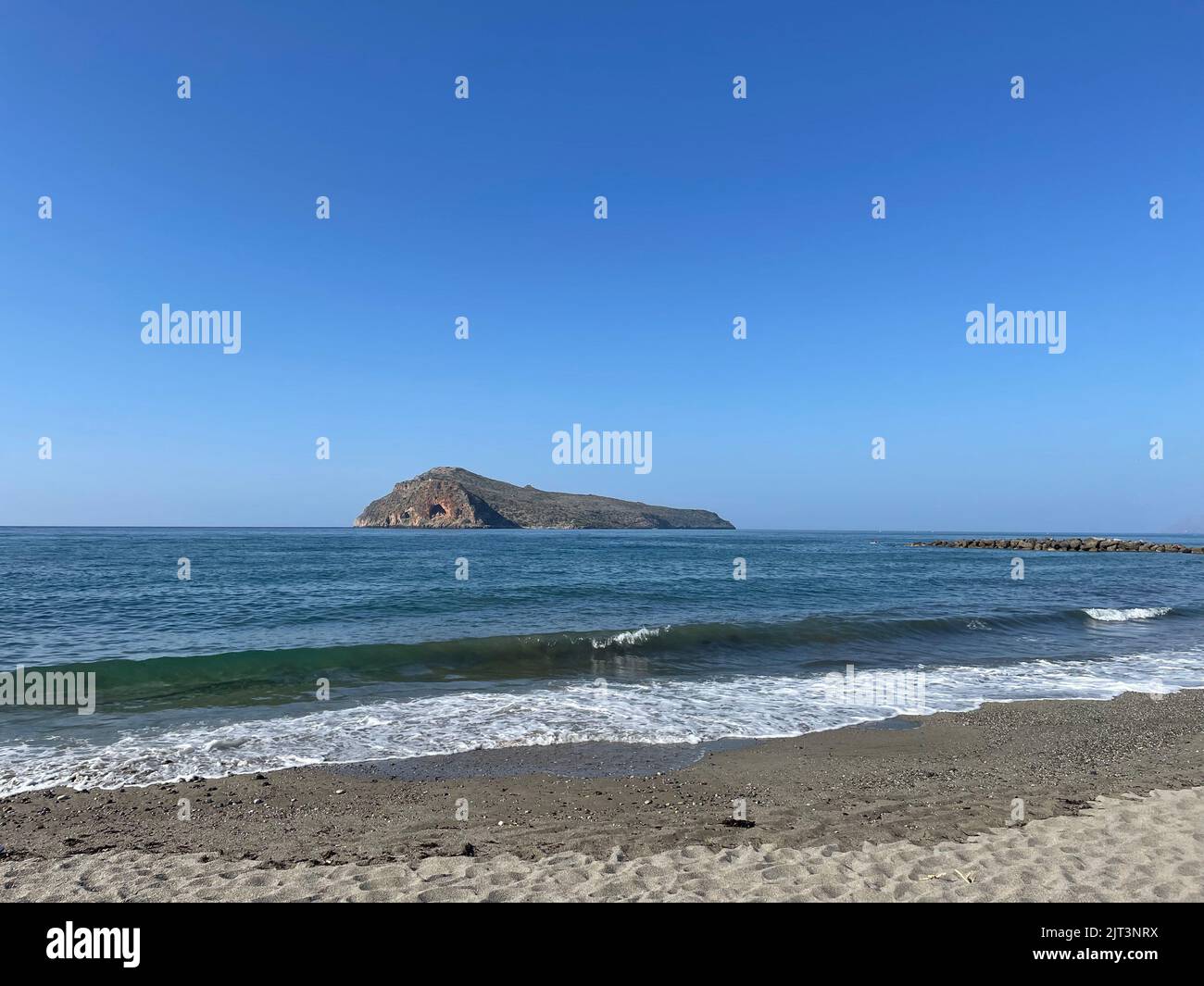 A beautiful view of a calm blue sea with low tides and a hill under a ...
