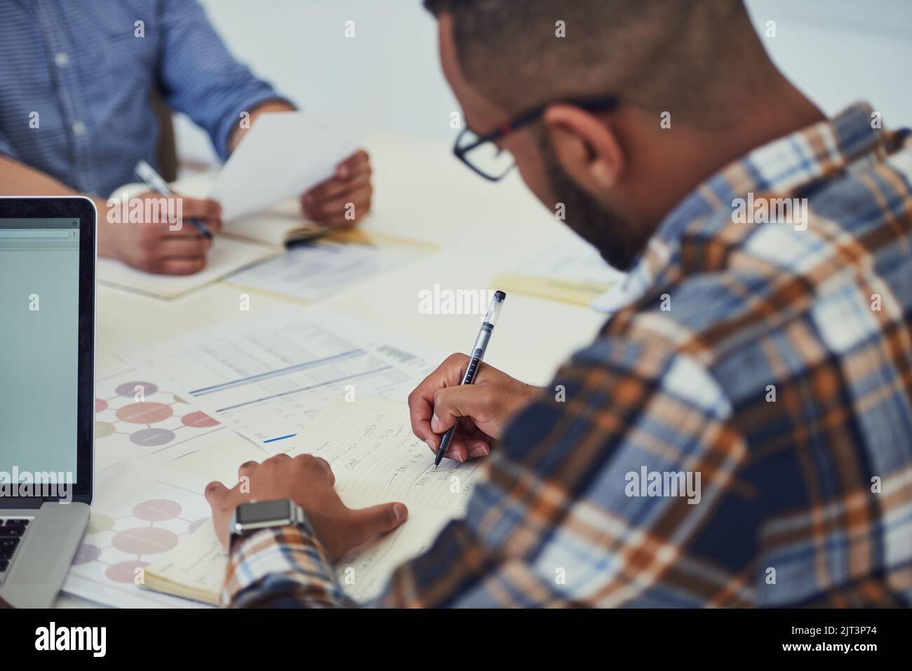 Taking notes from their meeting. a young designer writing notes during ...