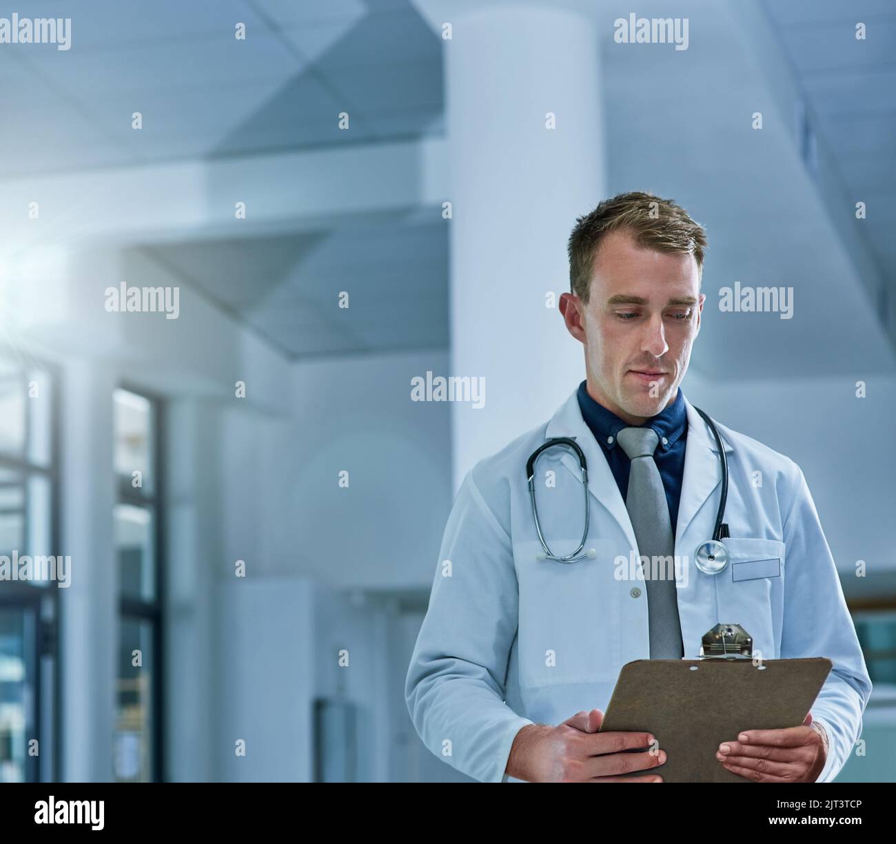 No detail is overlooked in his diagnosis. a young doctor reading the ... No detail is overlooked in his diagnosis. a young doctor reading the ...