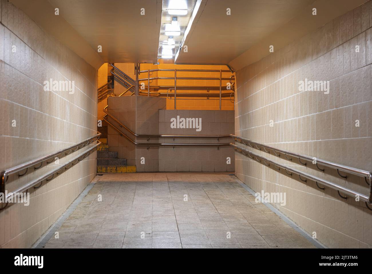 Modern underground passage glowing at night. Empty tiled underpass ...