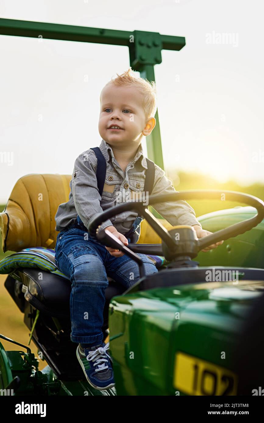 Farming is in his blood. an adorable little boy riding a tractor on a ...