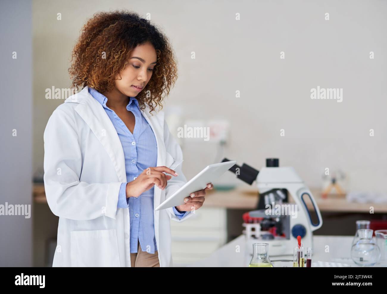 Collating The Data An Attractive Young Woman Capturing Data On Her Tablet In The Lab Stock