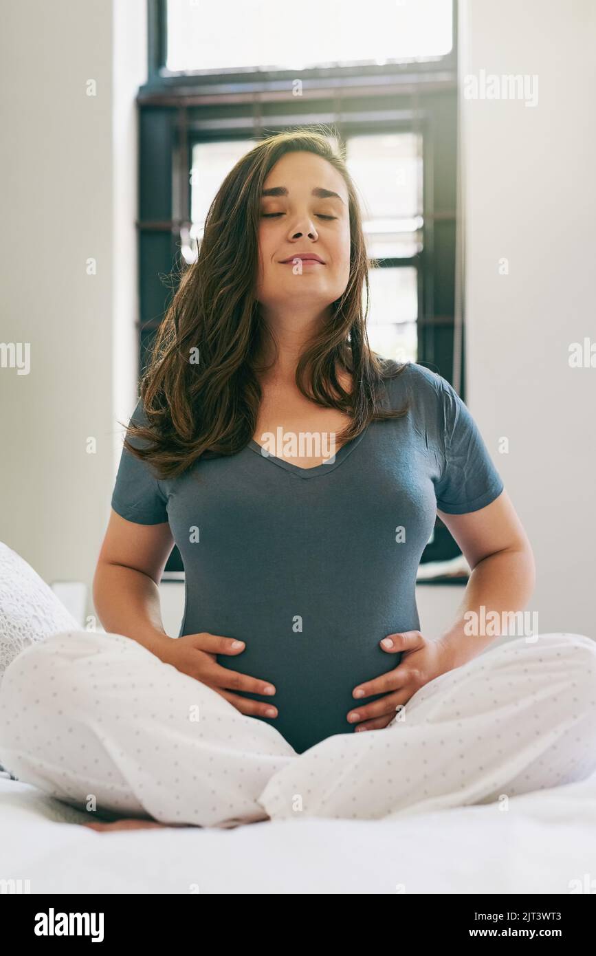 Keeping baby healthy. a young pregnant woman doing yoga while sitting ...