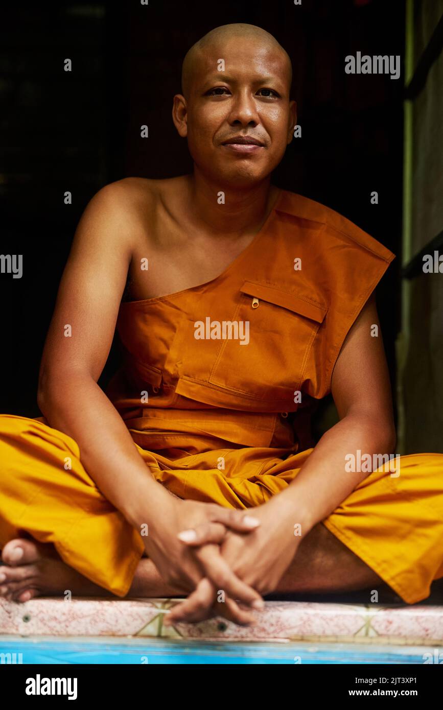 Happiness is living in the now. Portrait of a buddhist monk sitting in ...
