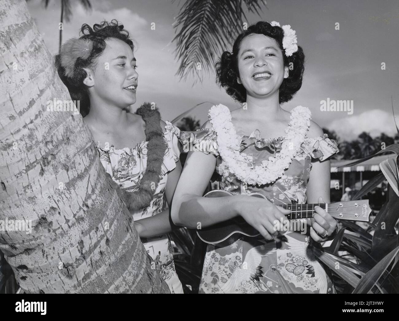 Two young women, one playing the ukulele in Hawaii, USA Stock Photo - Alamy