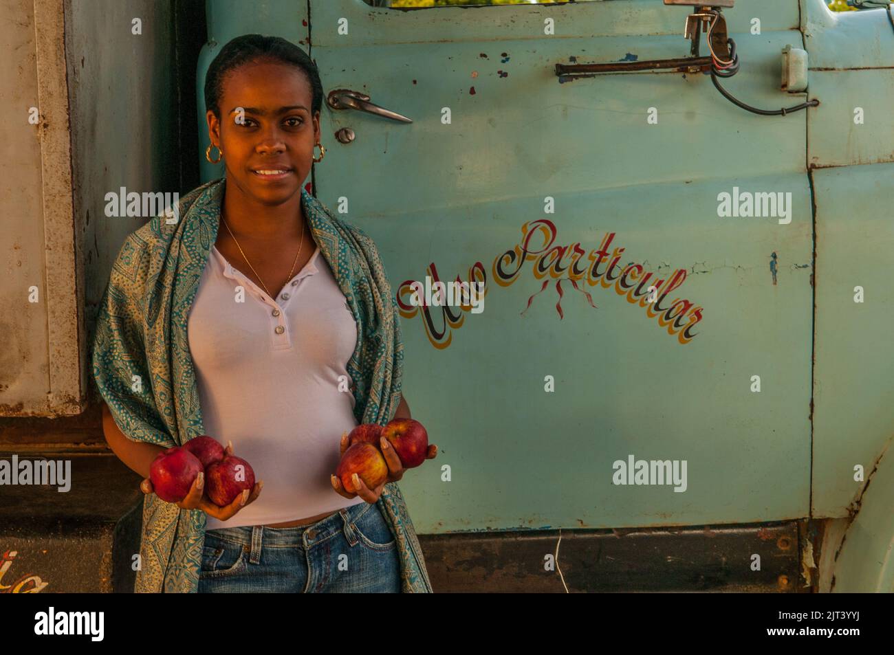 Cuban woman holding apples in front of a classic old truck w/ Spanish ...