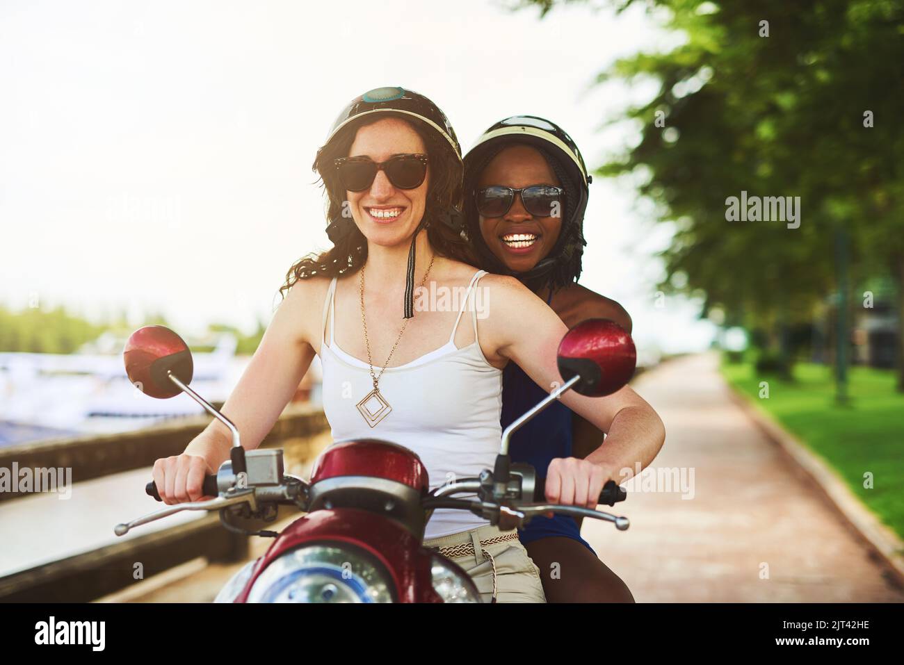 Feeling free to explore. two friends enjoying a ride on a scooter ...