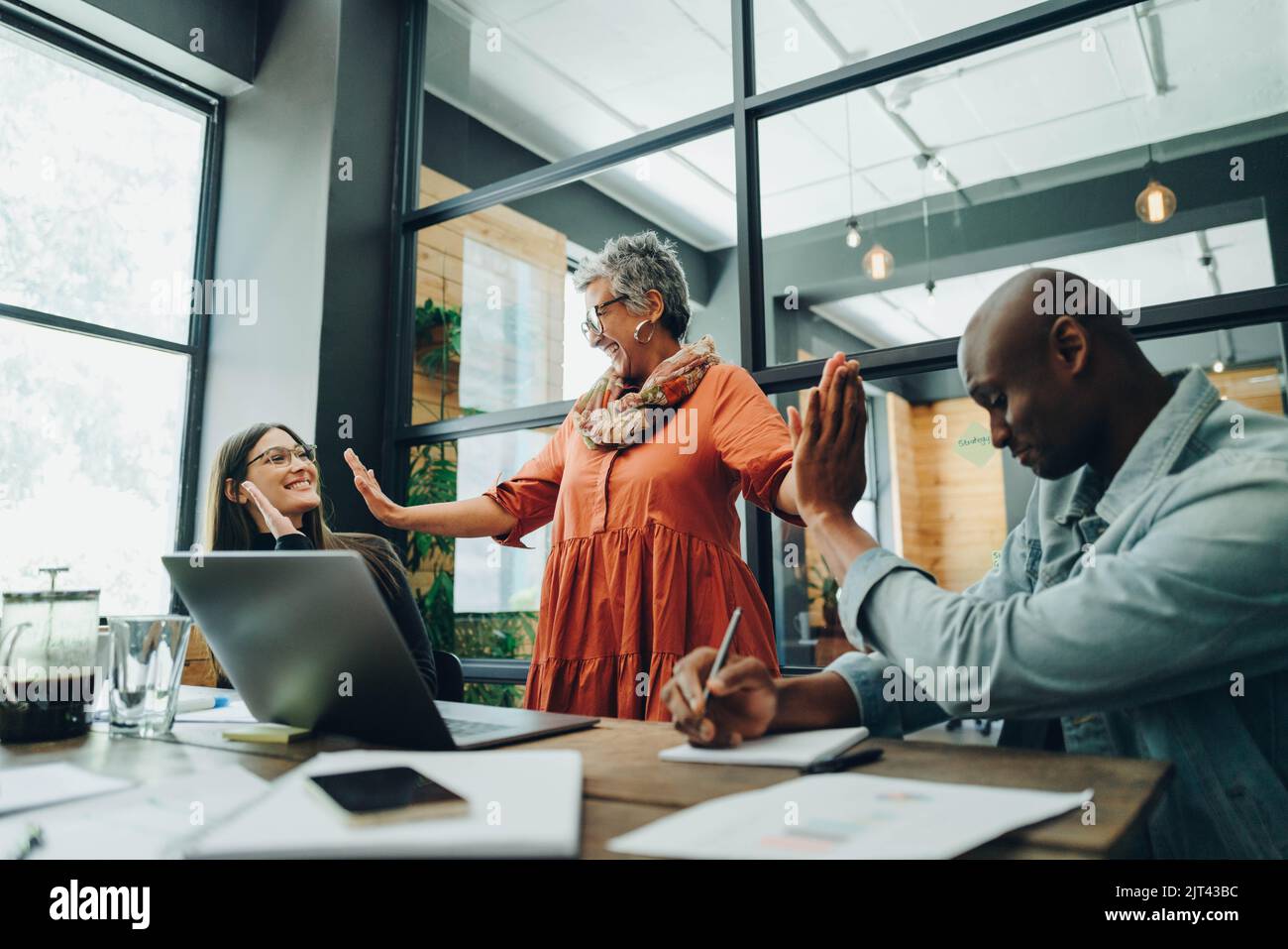 Successful businesspeople high fiving each other during a meeting in an ...