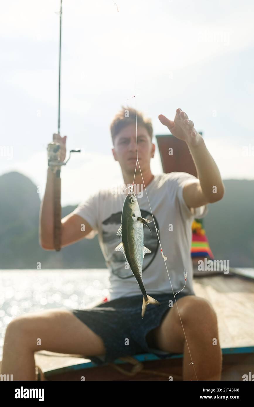 The first catch of many. a handsome young man fishing while out at sea ...