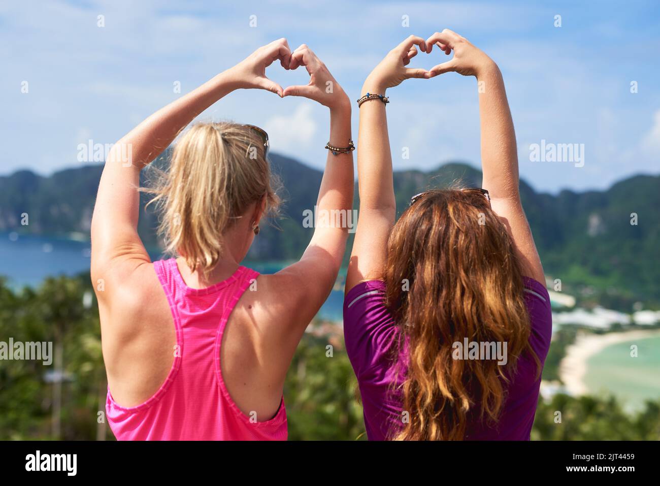 Keep on loving life. Rear view shot of two young woman making a heart ...