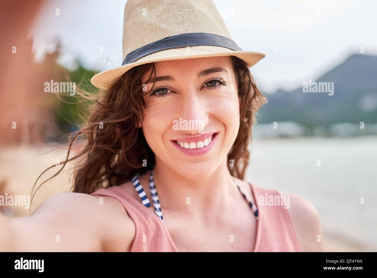 Beauty on the beach. Portrait of a happy young woman taking a selfie on ...