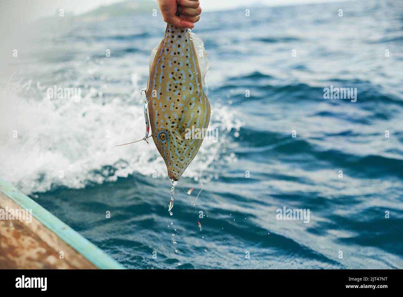 Catch of the day. an unrecognizable young man fishing while out at sea ...
