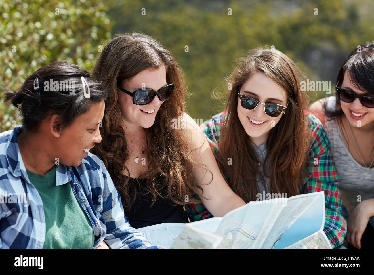Where to next. a group of friends reading a map together while out on a ...